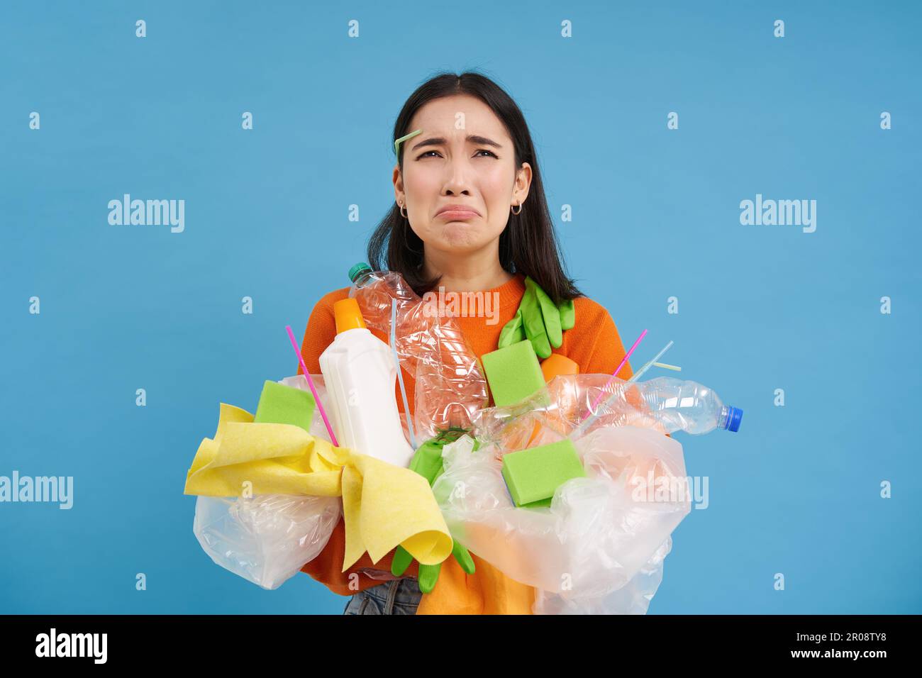 Crying asian female holding plastic waste, garbage in hands and looking ...