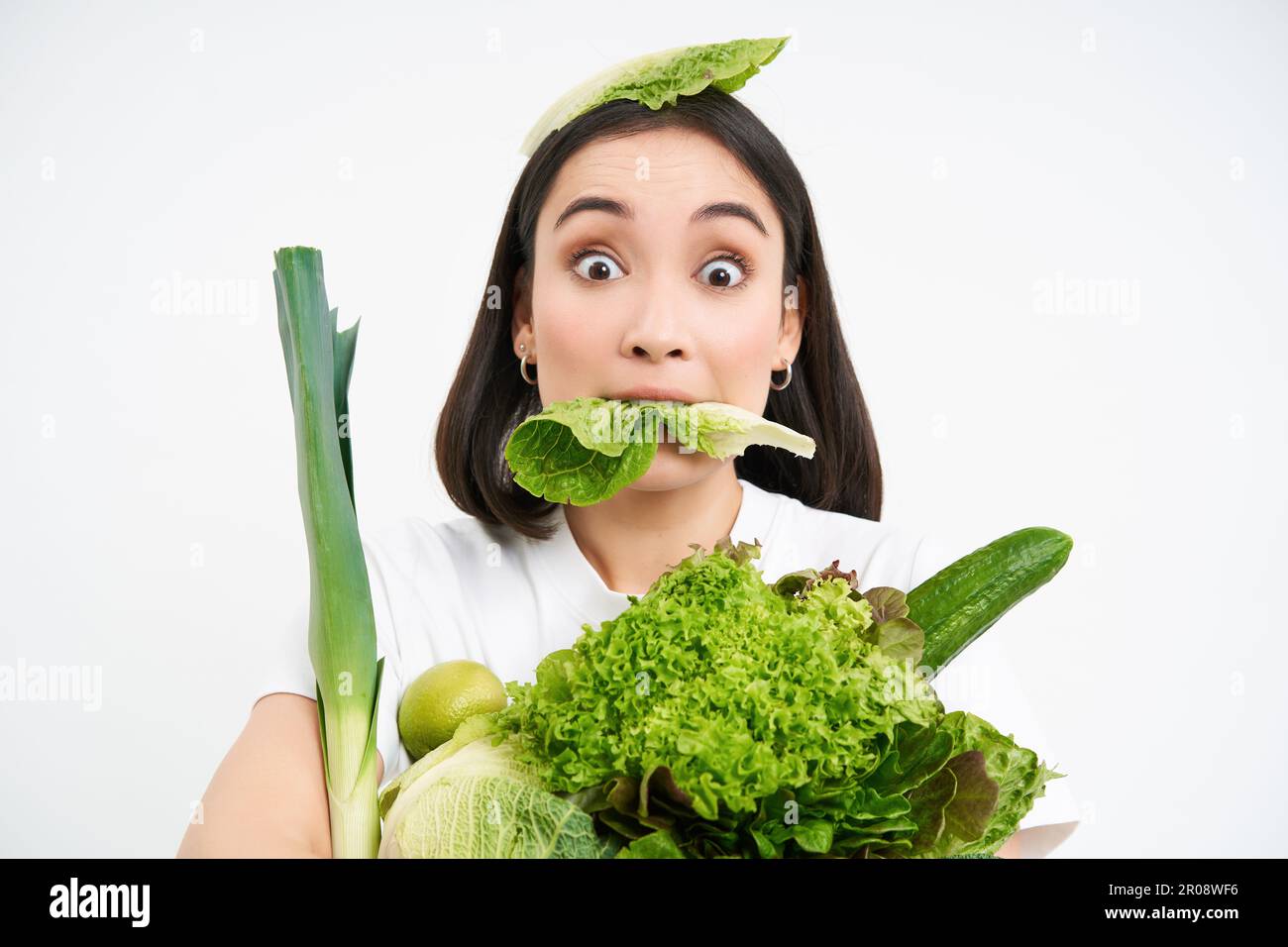 Close up portrait of asian girl munching lettuce leaf, holding green ...