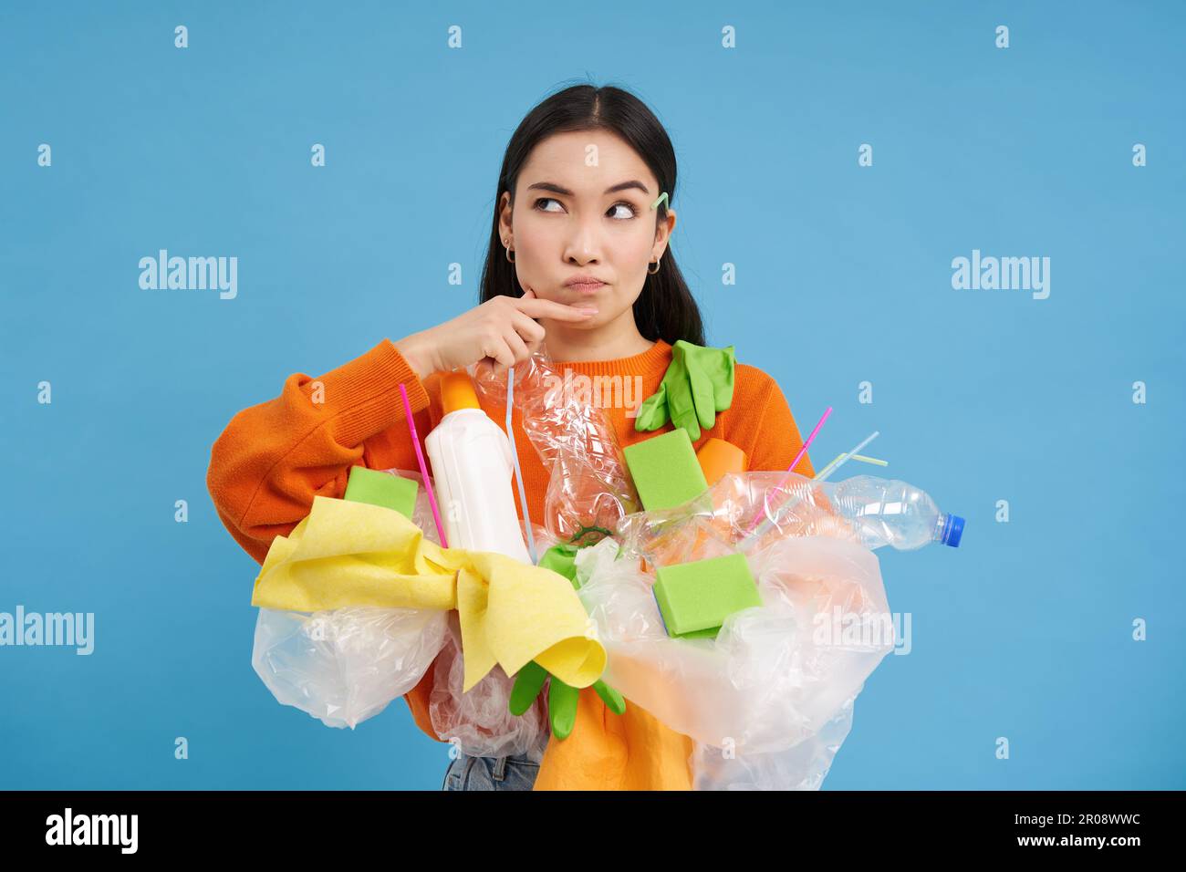 Asian woman holds plastic waste and makes thinking face, ponders how to ...