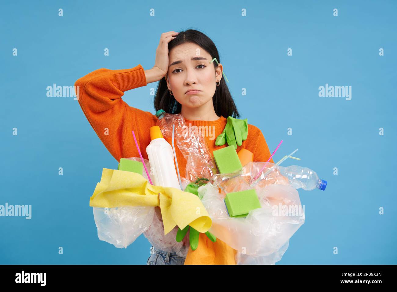 Woman with complicated face, looking confused at plastic garbage ...
