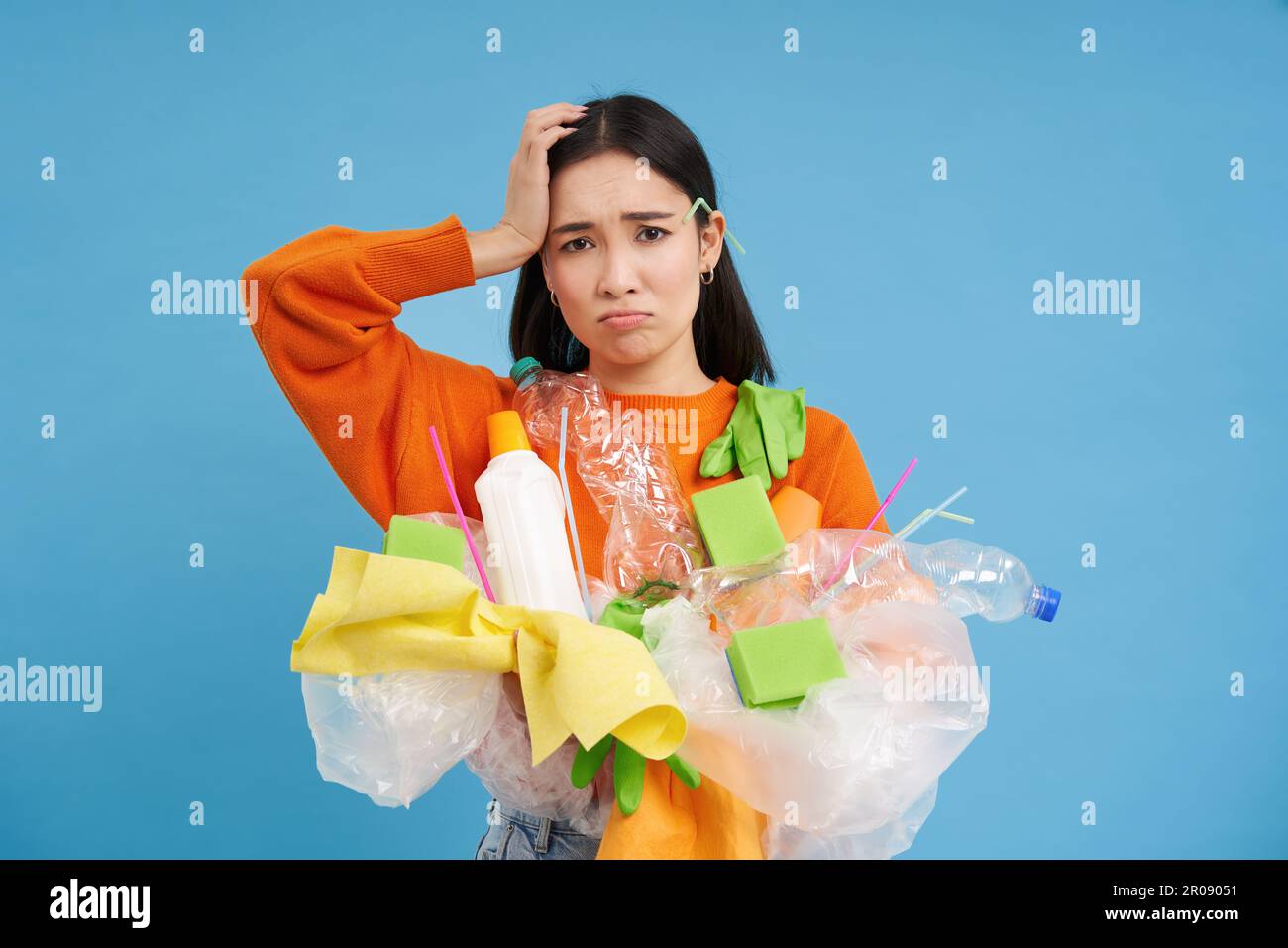 Woman with complicated face, looking confused at plastic garbage ...