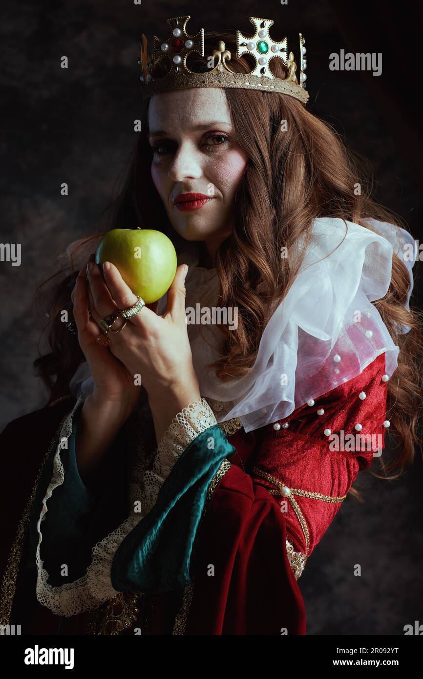 medieval queen in red dress with green apple, white collar and crown on ...