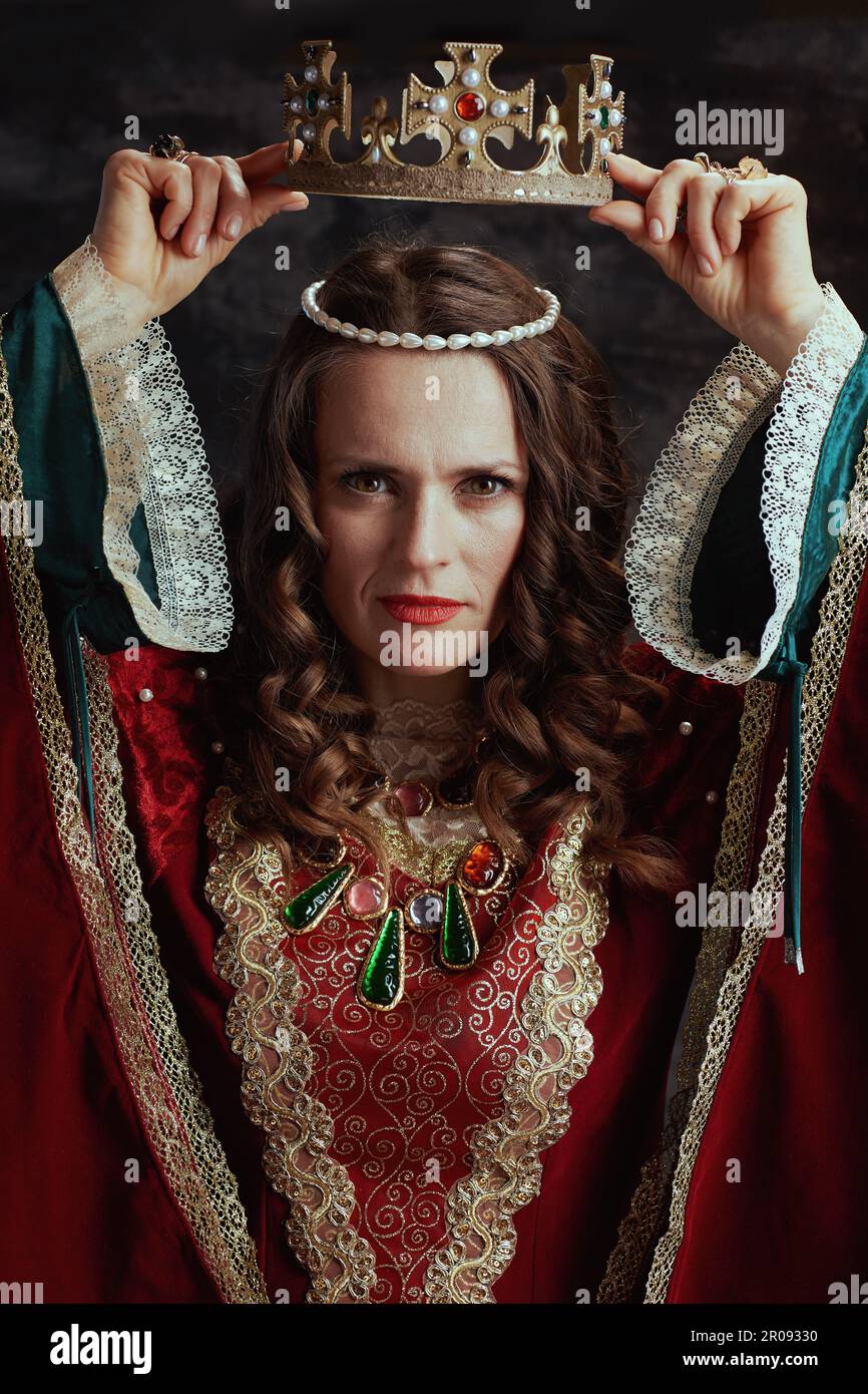 medieval queen in red dress with crown on dark gray background Stock ...