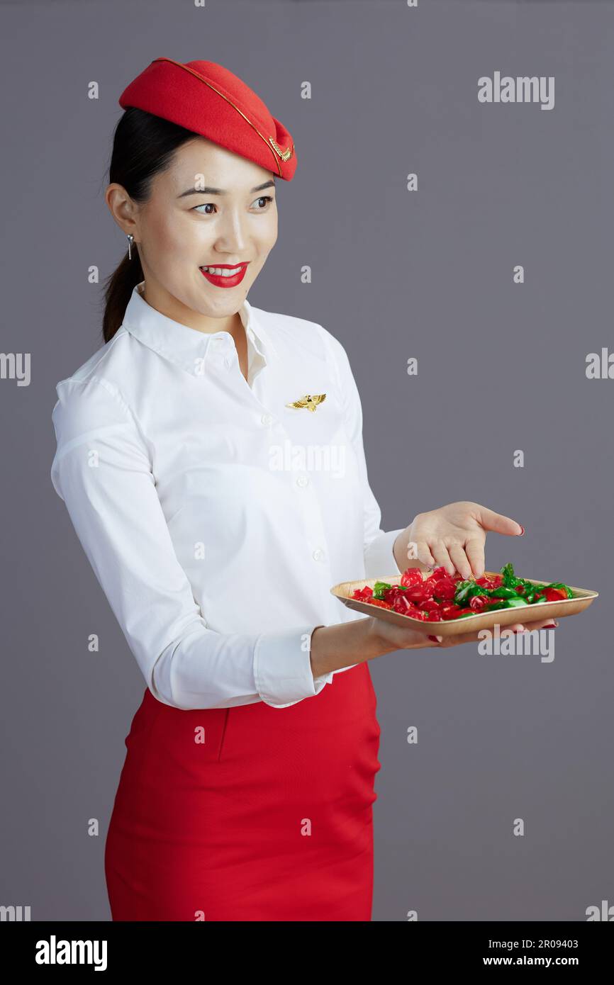 happy stylish asian female air hostess in red skirt and hat uniform ...