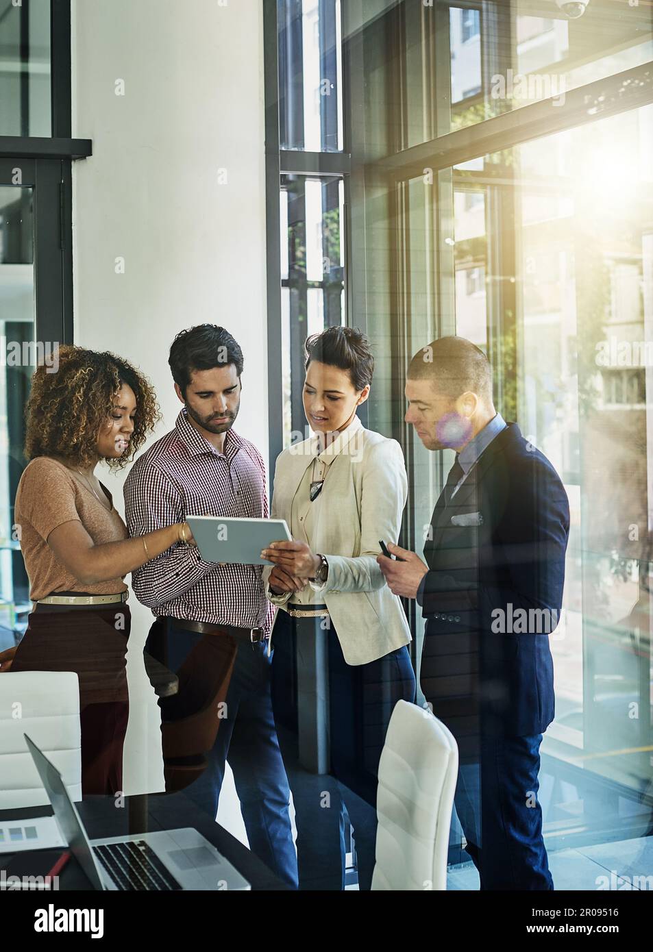 Prepping before the meeting. a group of colleagues using a tablet while ...
