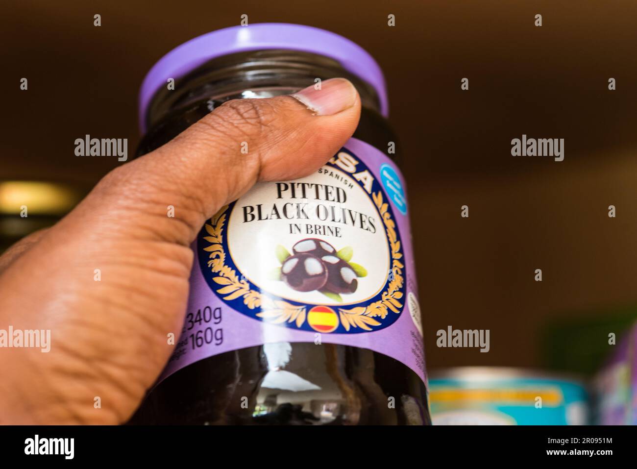 Adult male picking a jar of olives from home shelf Stock Photo - Alamy