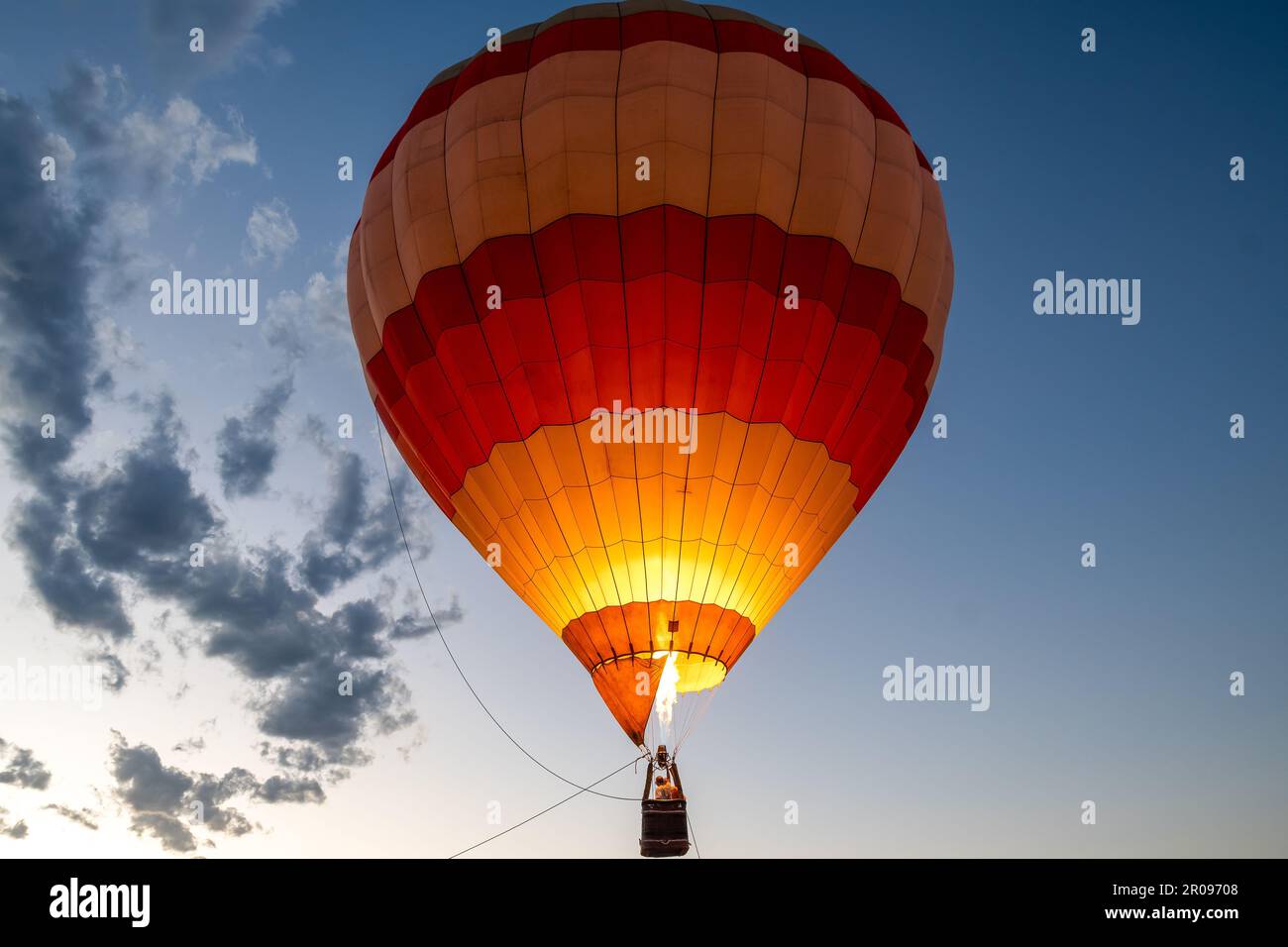 An aerial view of a colorful hot air balloon drifting through the sky ...