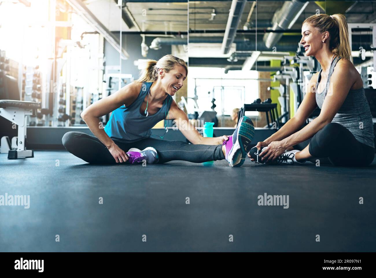 Stretching improves flexibility. two women chatting while stretching ...