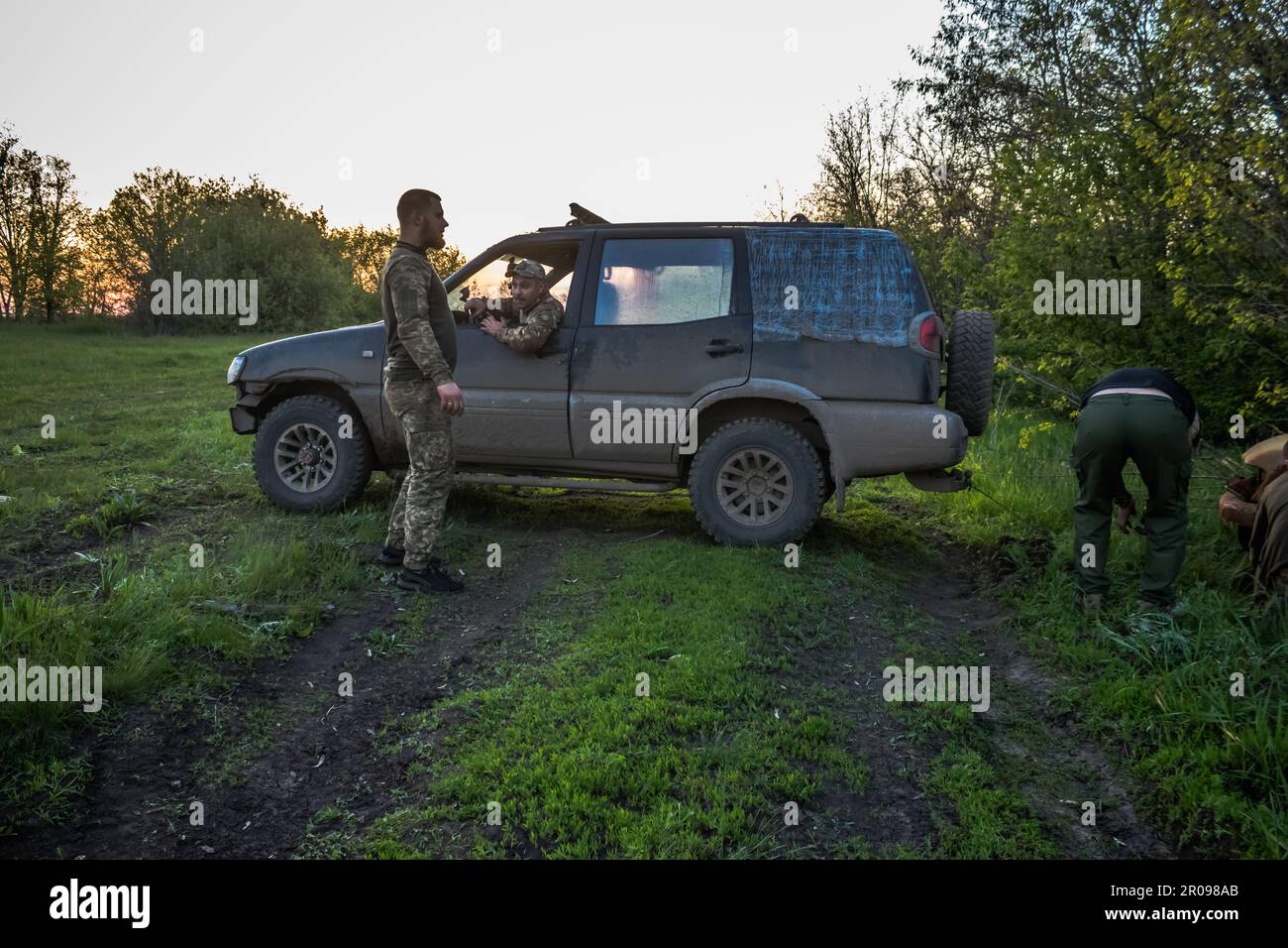 Ukrainian soldiers loading a car damaged by artillery fire in the ...