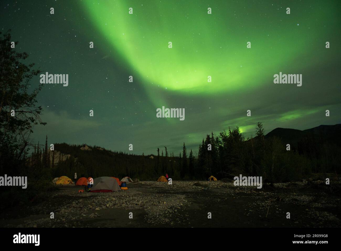 Northern Lights over camping tents, on a dry river bed in Nahanni ...