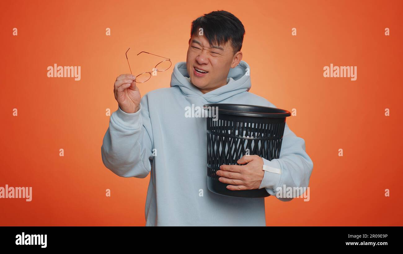Asian man taking off, throwing out glasses into bin after medical ...
