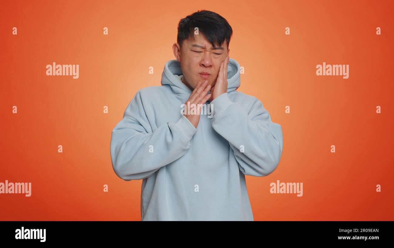 Asian man touching sore cheek suffering from toothache cavities or ...