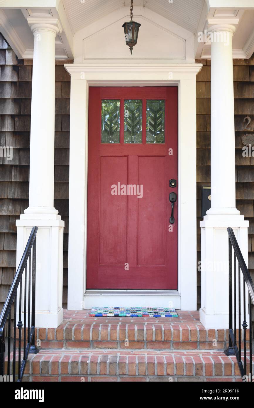 A red door on a house that has cedar shingles and white columns Stock ...