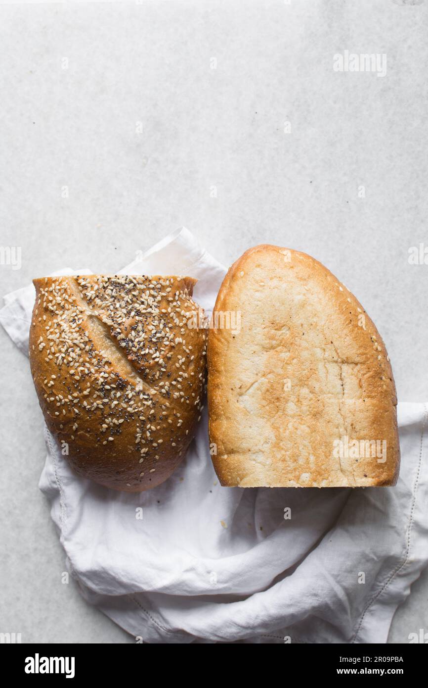 Loaf of artisan bread topped with sesame seeds cut into half, top view ...