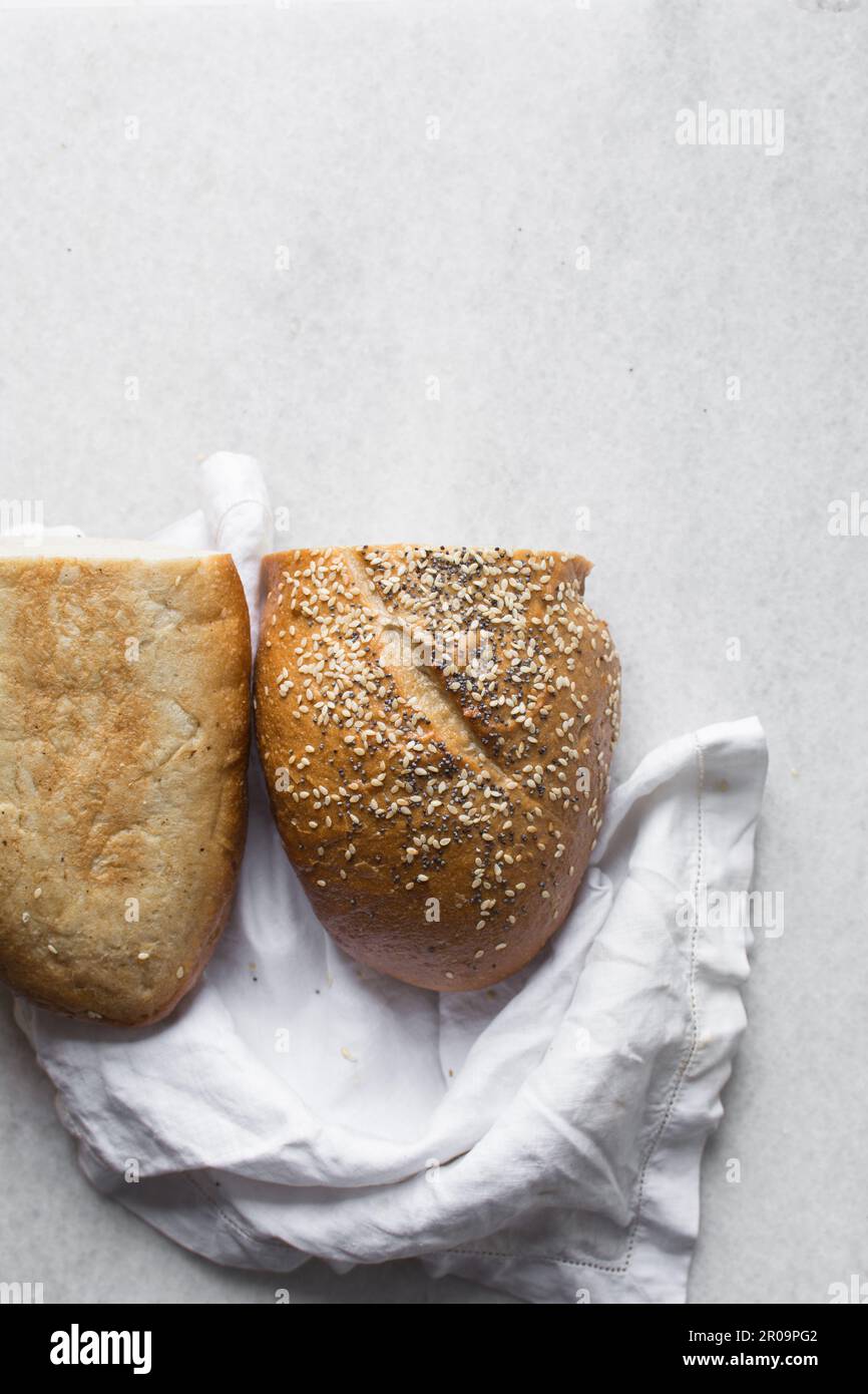 Loaf of artisan bread topped with sesame seeds cut into half, top view ...
