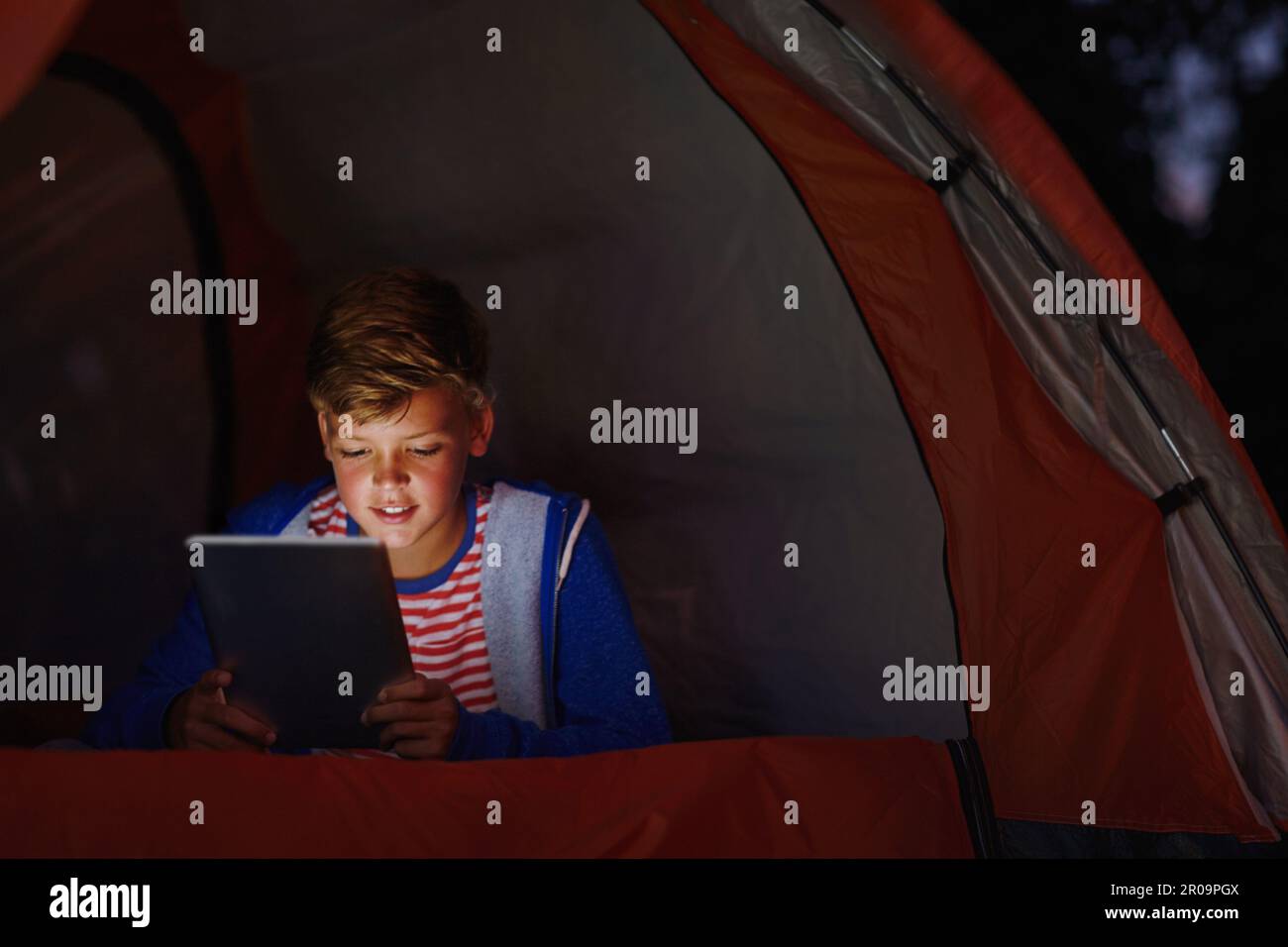 Tent-ertainment. a young boy using a digital tablet while camping Stock ...