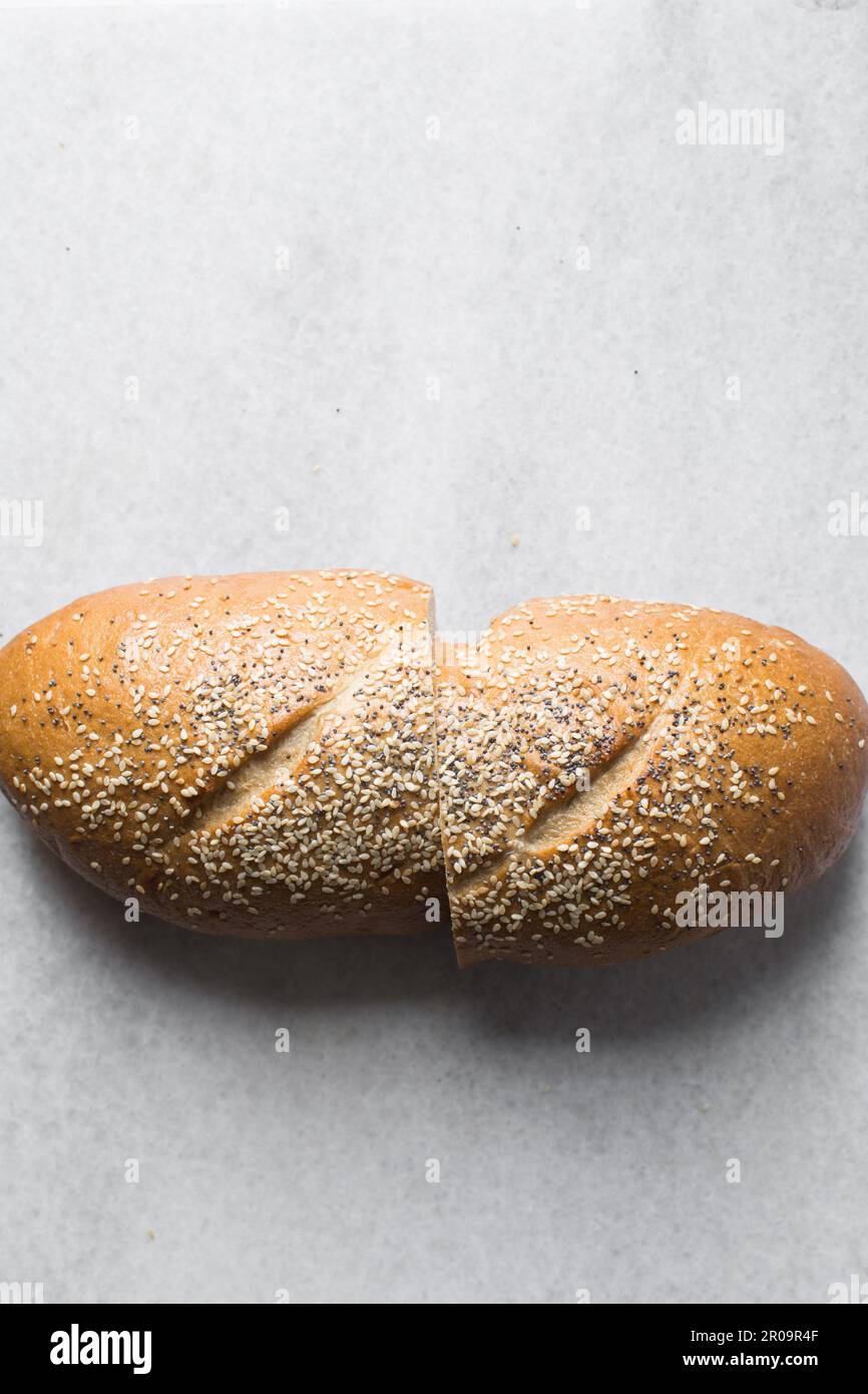 Loaf of artisan bread topped with sesame seeds cut into half, top view ...