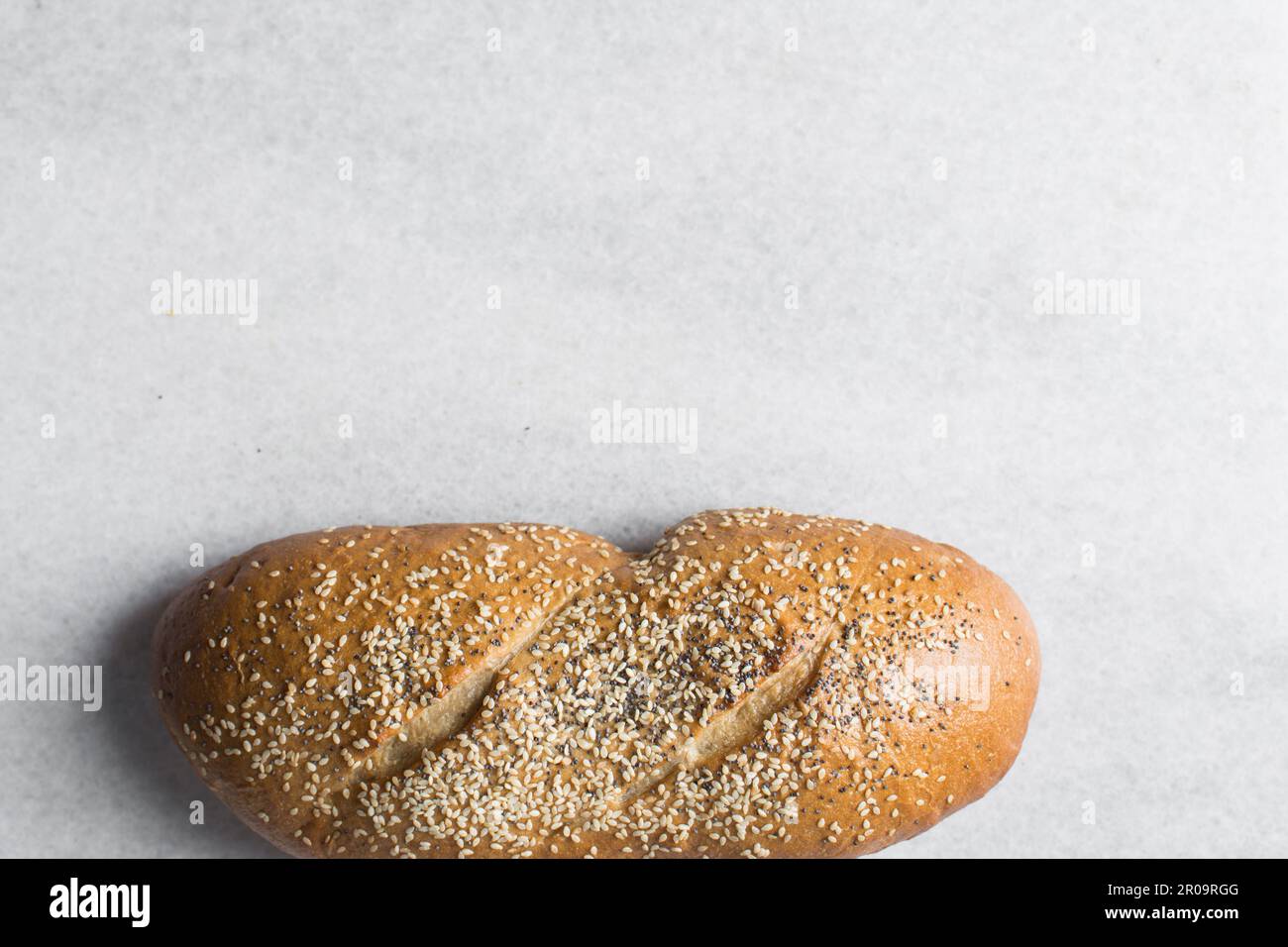 Loaf of artisan bread topped with sesame seeds on a marble countertop ...
