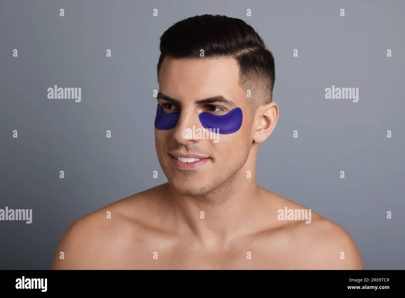 Man with blue under eye patches on grey background Stock Photo - Alamy