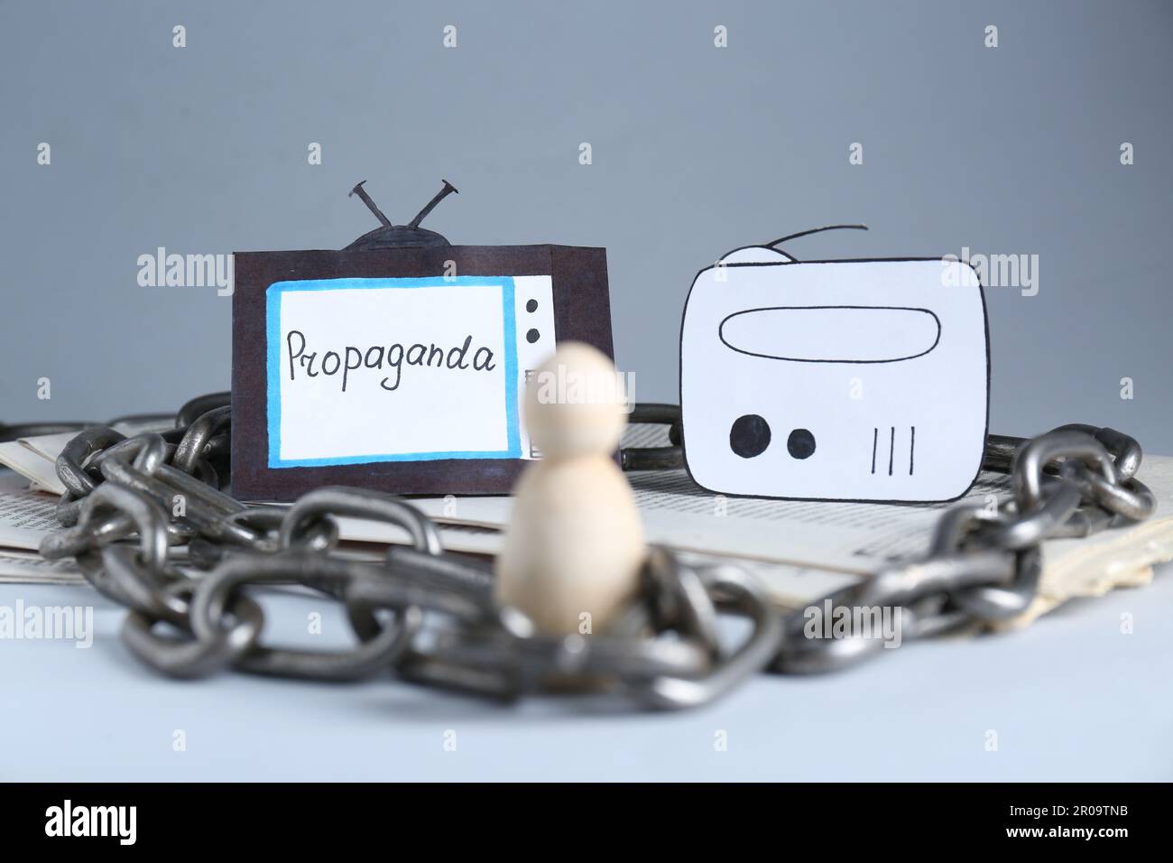 Propaganda concept. Human mired in media field. Chained wooden figure ...