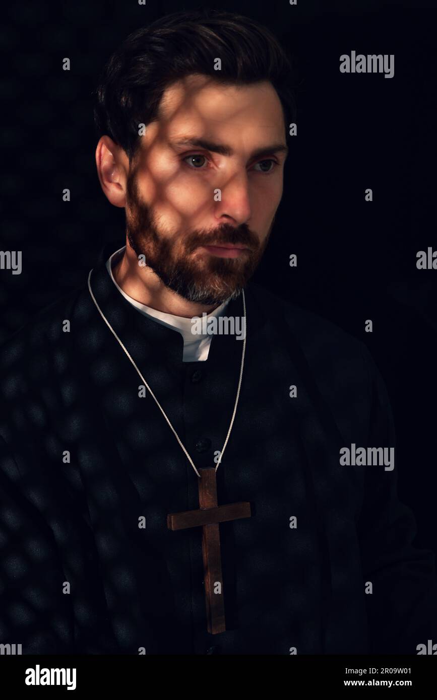 Catholic priest wearing cassock in confessional booth Stock Photo - Alamy