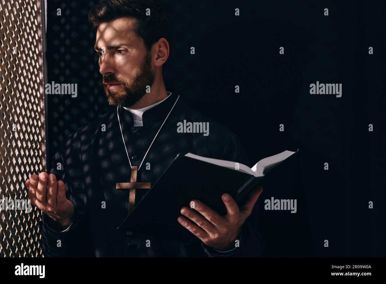 Catholic priest in cassock holding Bible and talking to parishioner in ...