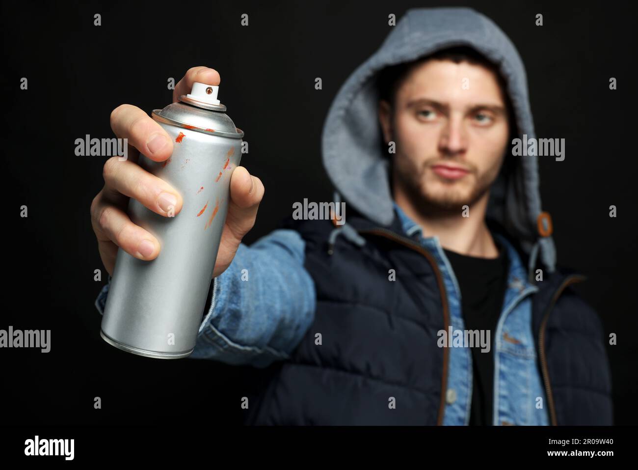 Handsome man holding used spray paint against black background Stock ...