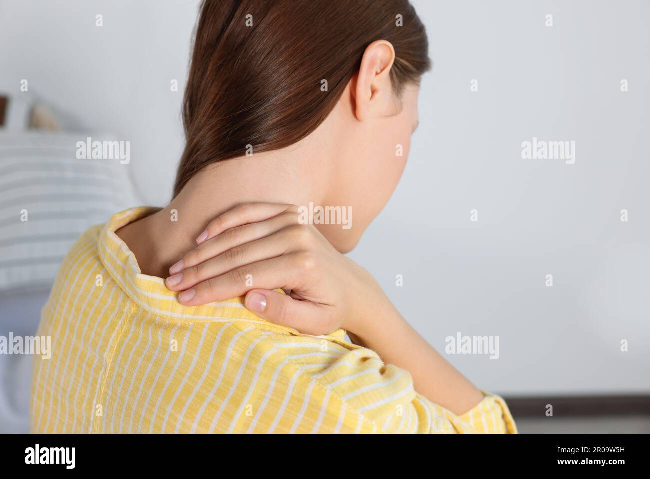 Woman suffering from neck pain in room Stock Photo - Alamy