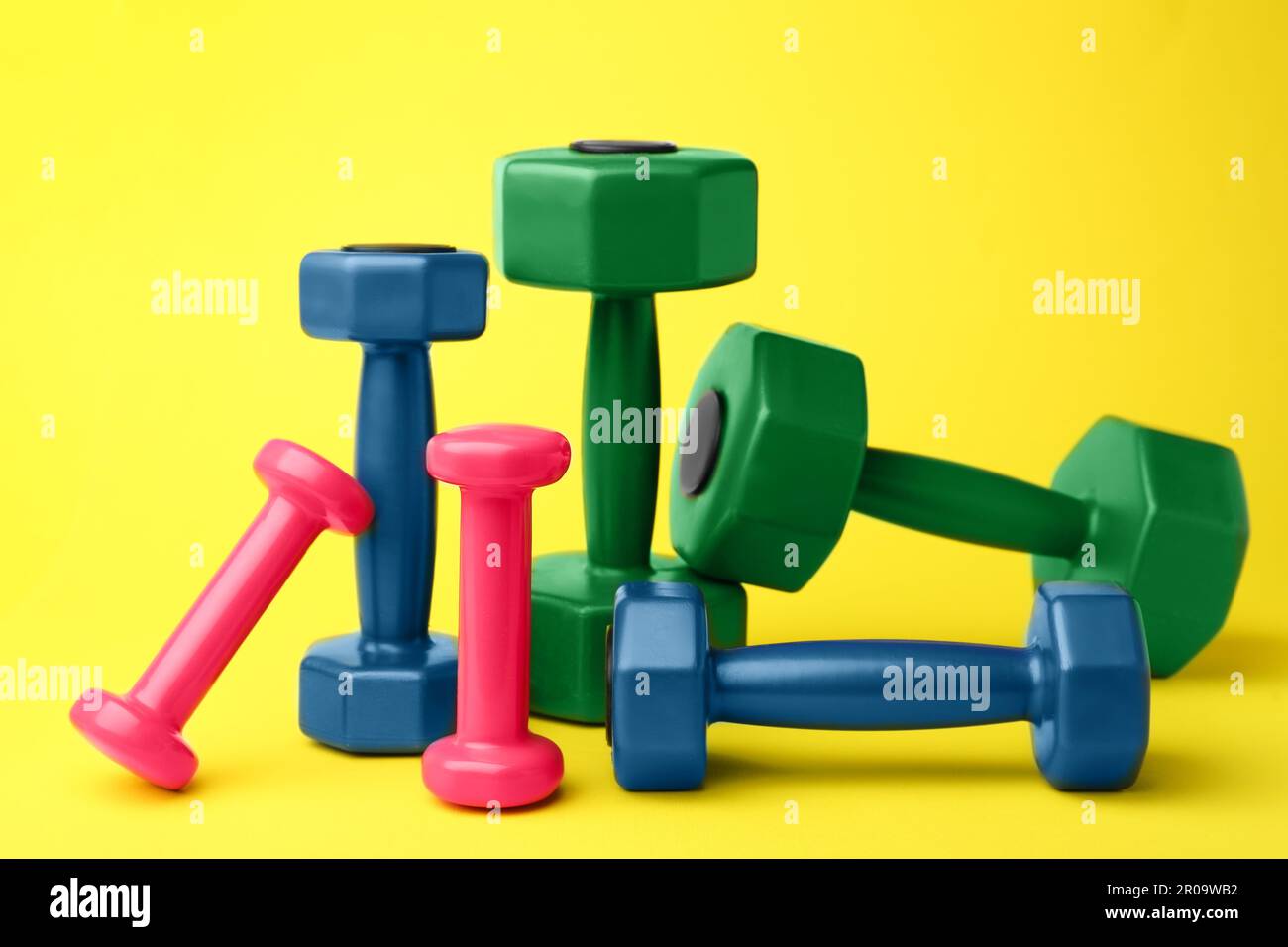 Many different stylish dumbbells on yellow background Stock Photo - Alamy