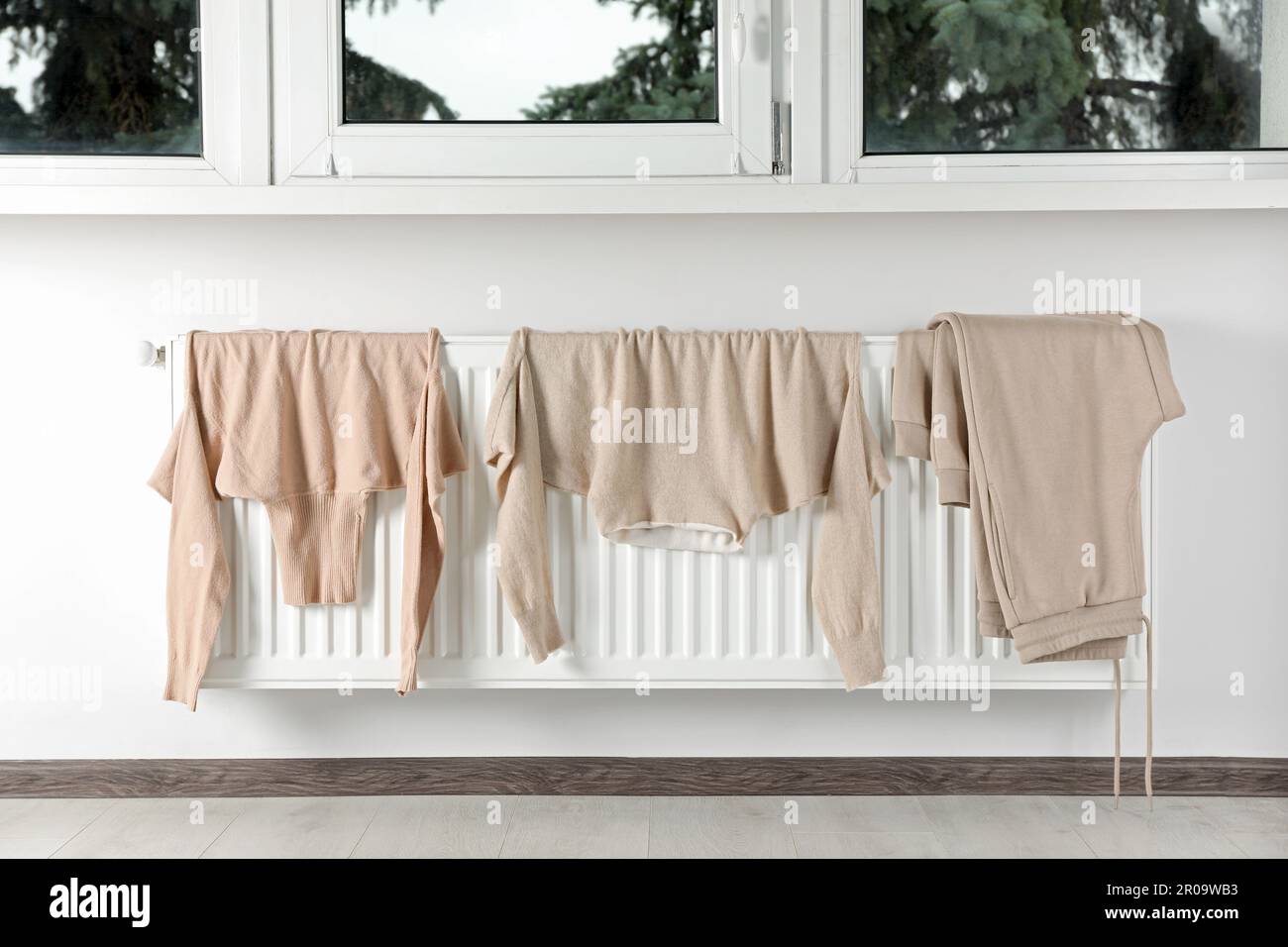 Clean clothes hanging on white radiator in room Stock Photo - Alamy