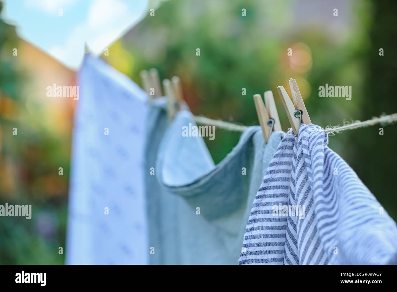Washing line with drying shirts against blurred background, focus on clothespin Stock Photo - Alamy
