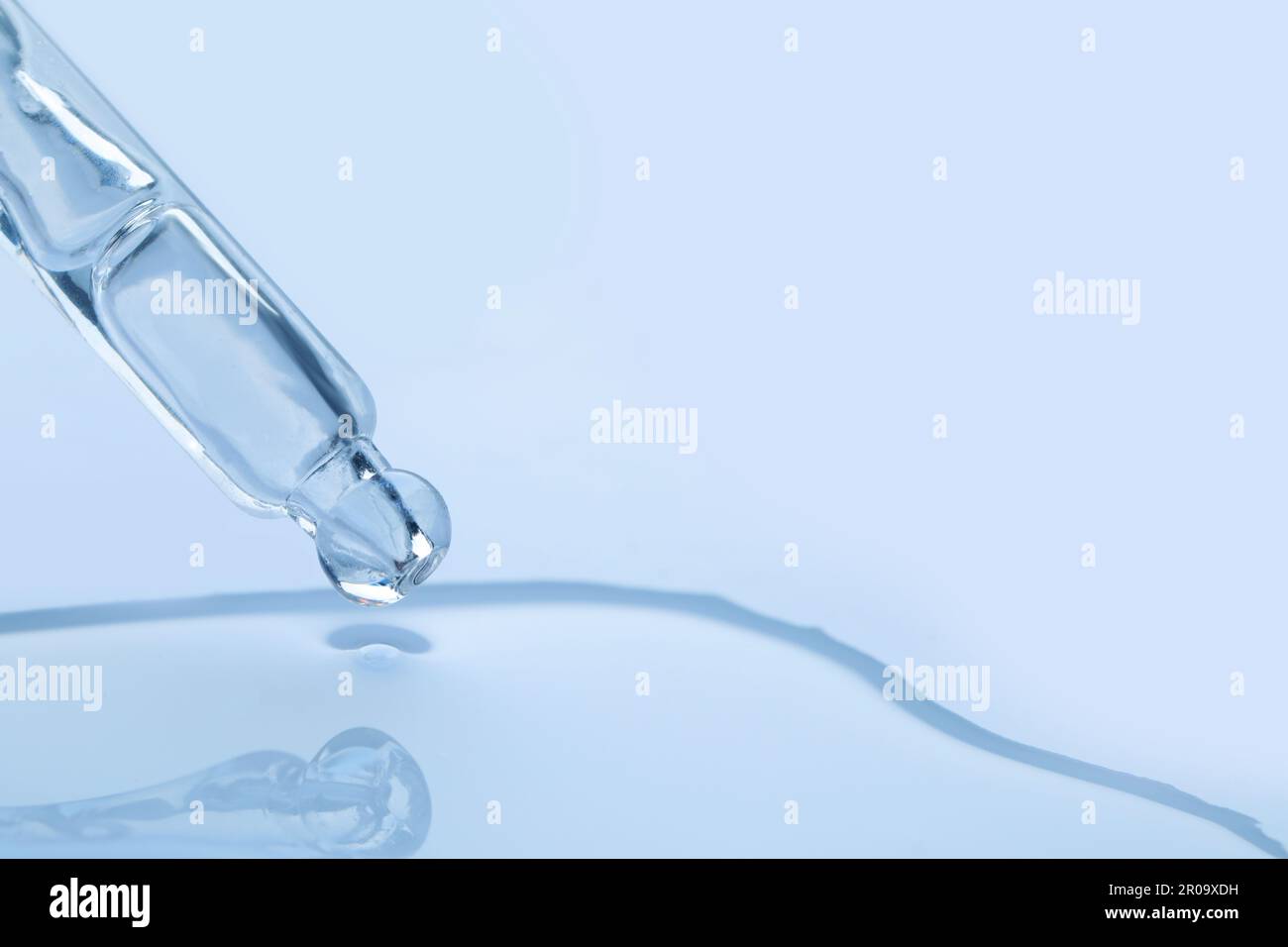 Dripping face serum from pipette on white background, closeup. Space ...