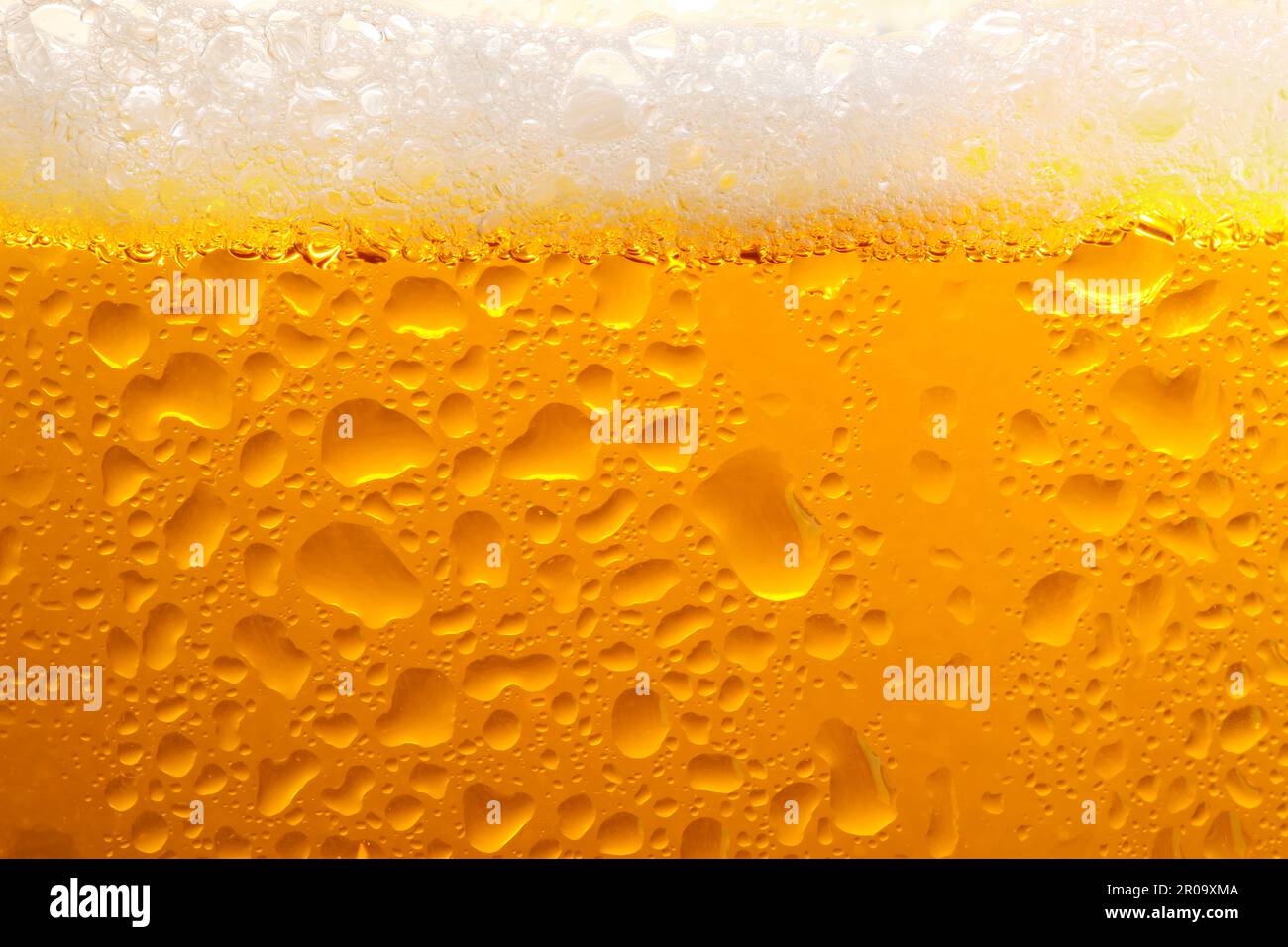 Glass of tasty cold beer with foam and condensation drops as background ...