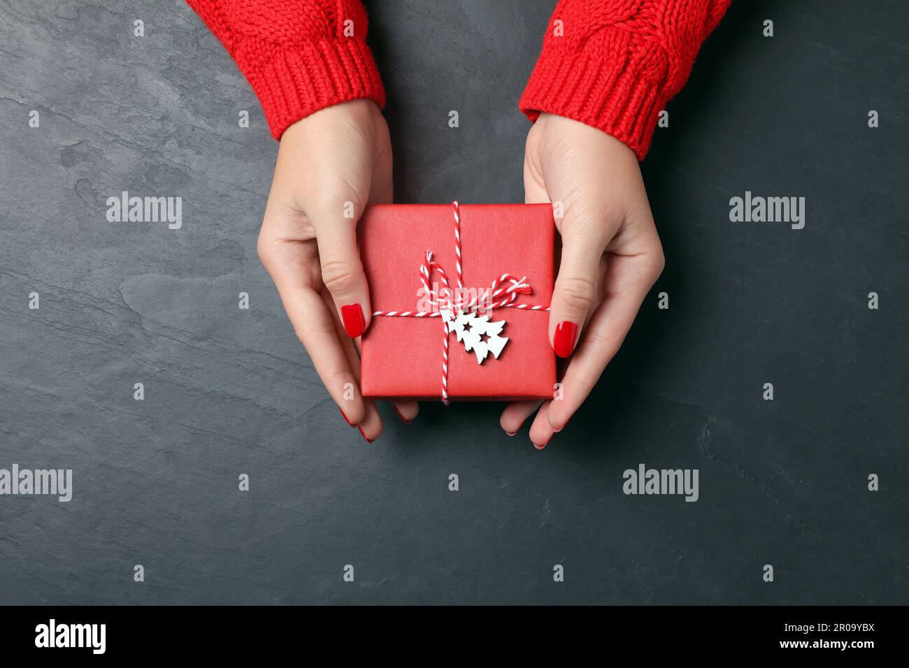 Christmas present. Woman with gift box at black table, top view Stock ...