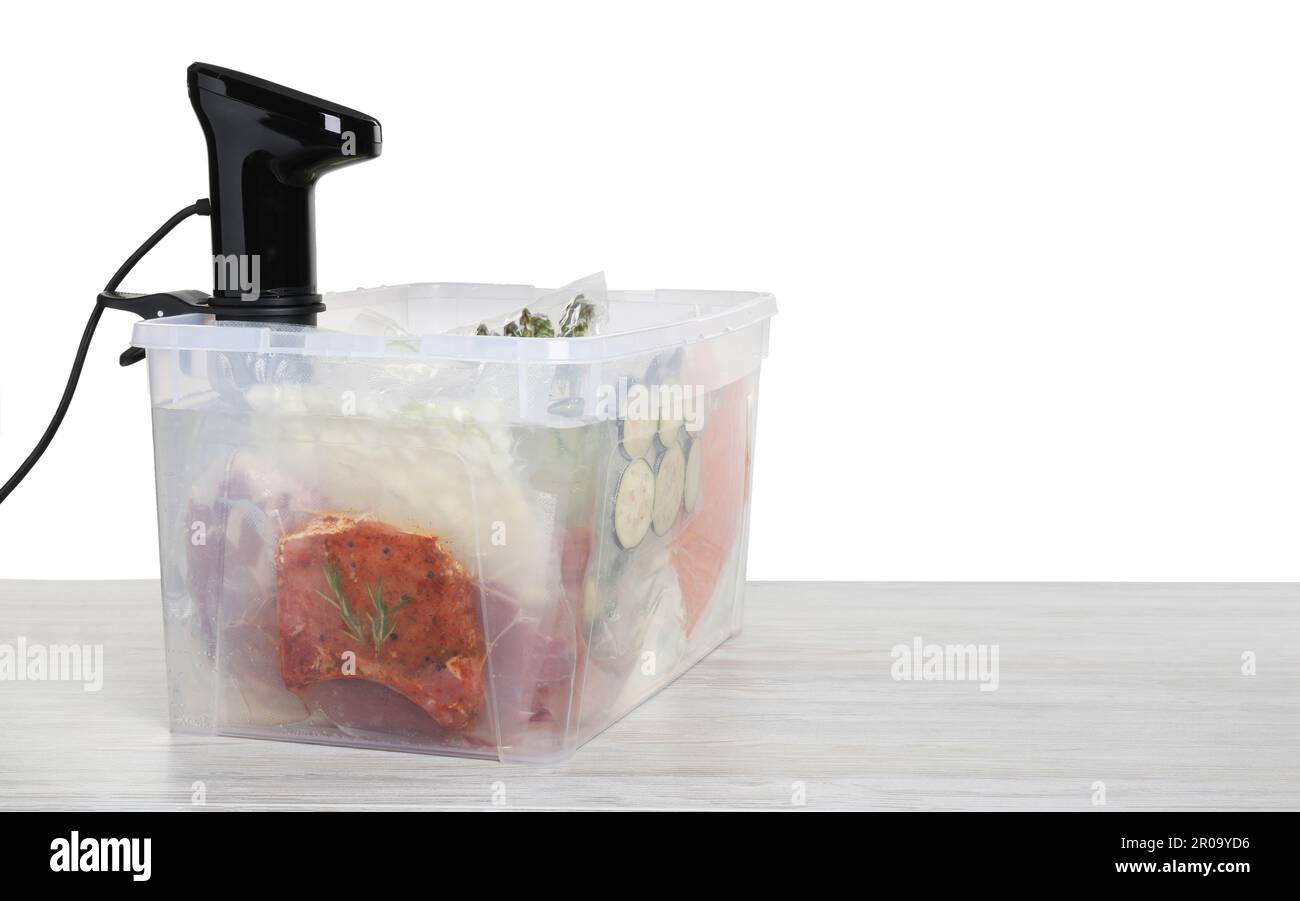 Sous vide cooker and vacuum packed food products in box on wooden table ...