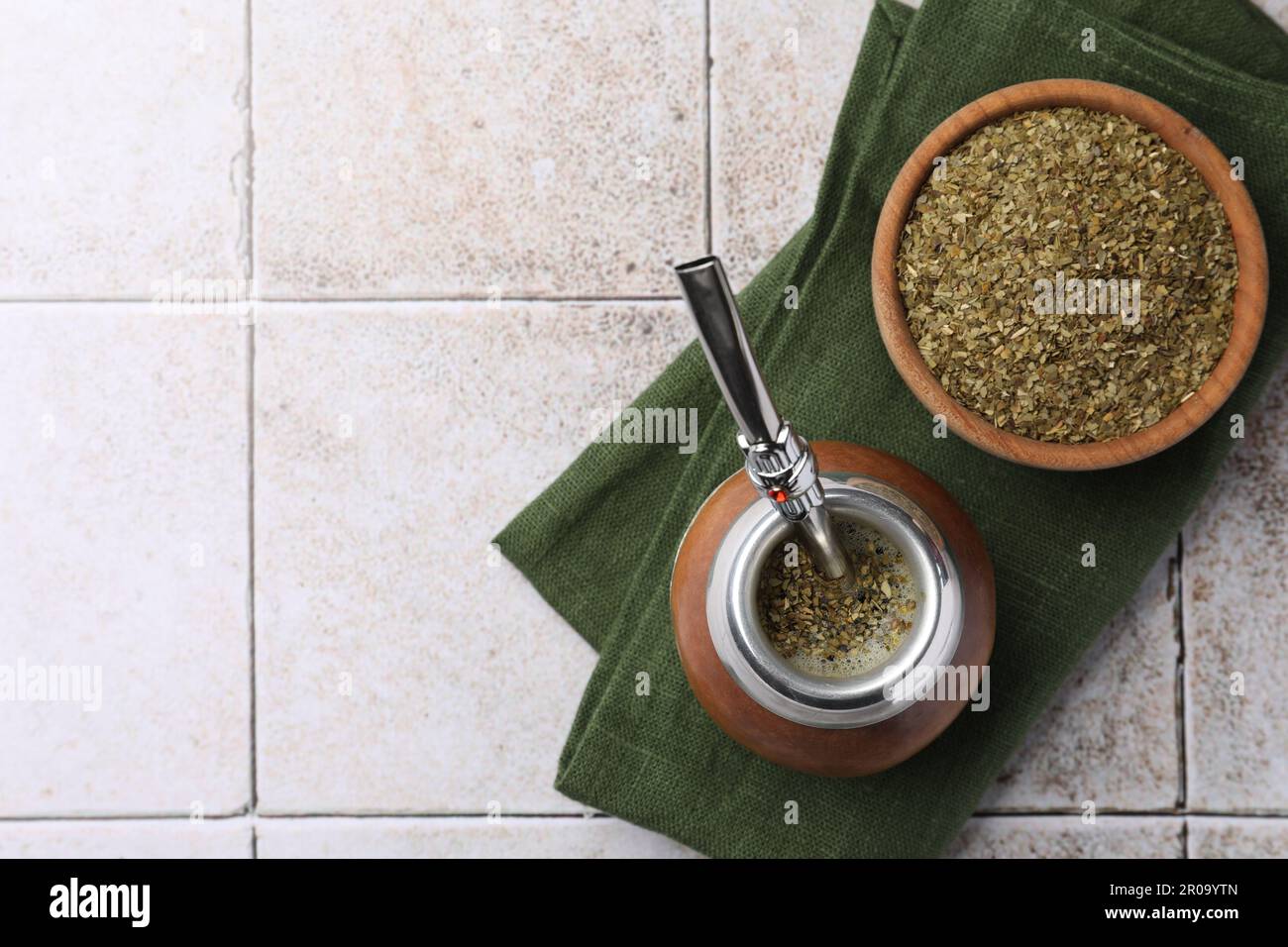 Calabash with bombilla, bowl of mate tea leaves and cloth on tiled ...