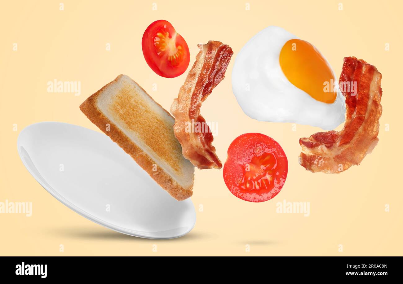 Tasty fried chicken egg, bacon, tomato and toasted bread falling into ...