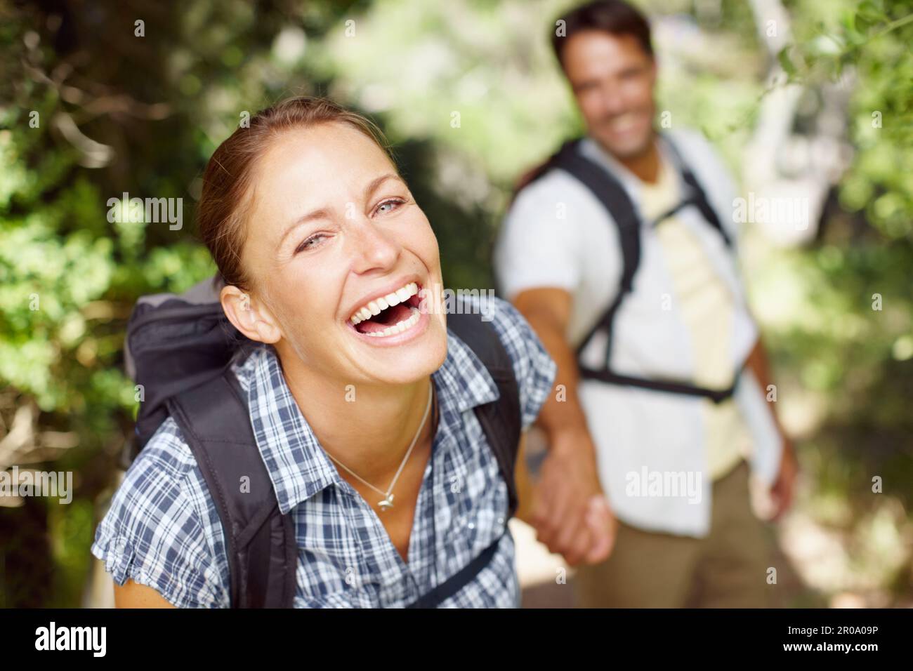 Almost there. Portrait of a young woman laughing and wearing a backpack ...