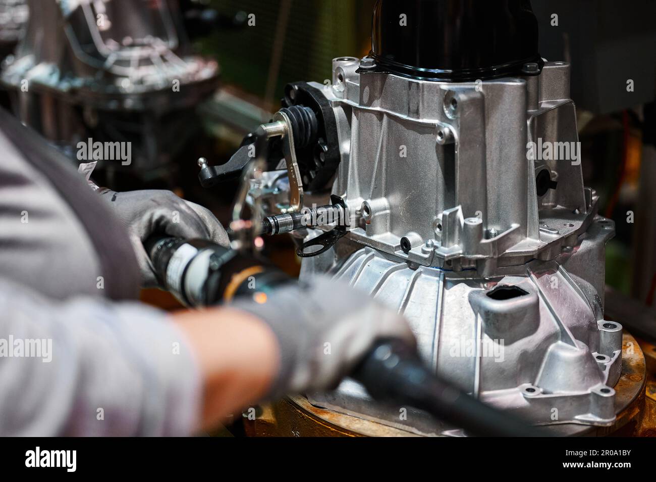 Worker connects car engine gearbox details on shop conveyor Stock Photo ...