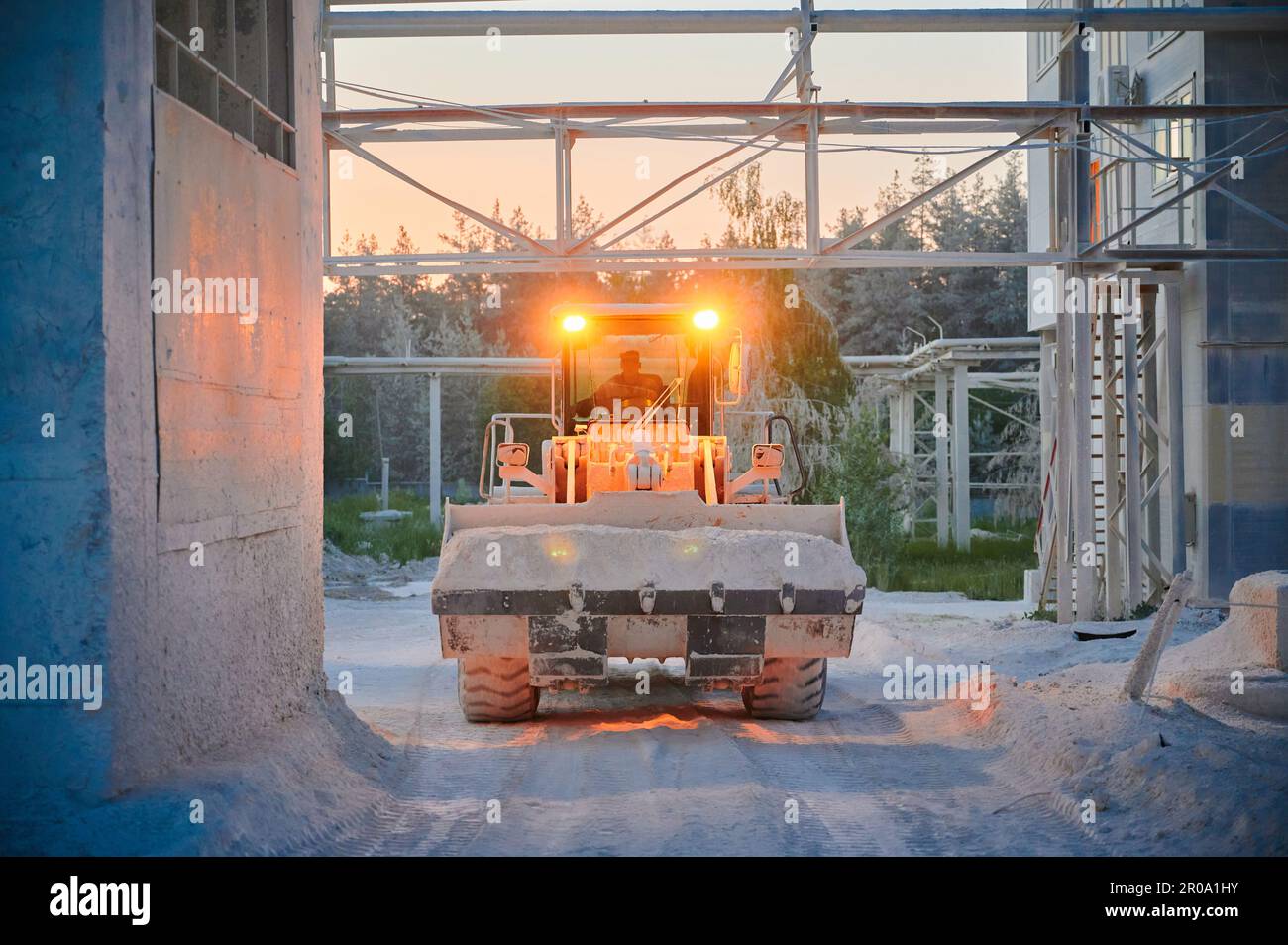 Wheel loader with bright lights transports lime in bucket Stock Photo ...