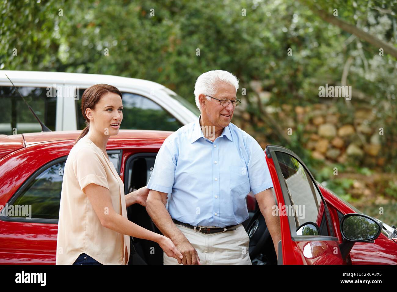 Taking her dad on a trip. a woman helping her senior father out of the ...
