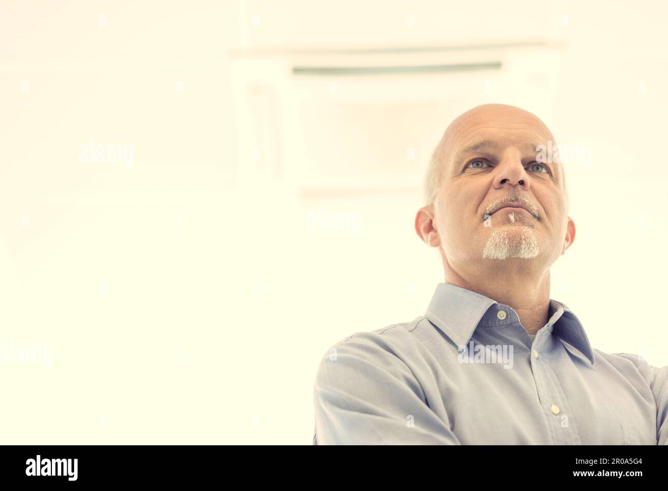 View from below of a mature man's face peering into the distance ...