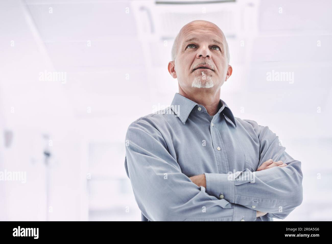 Frontal, view from below, man with arms folded very serious. He is in ...