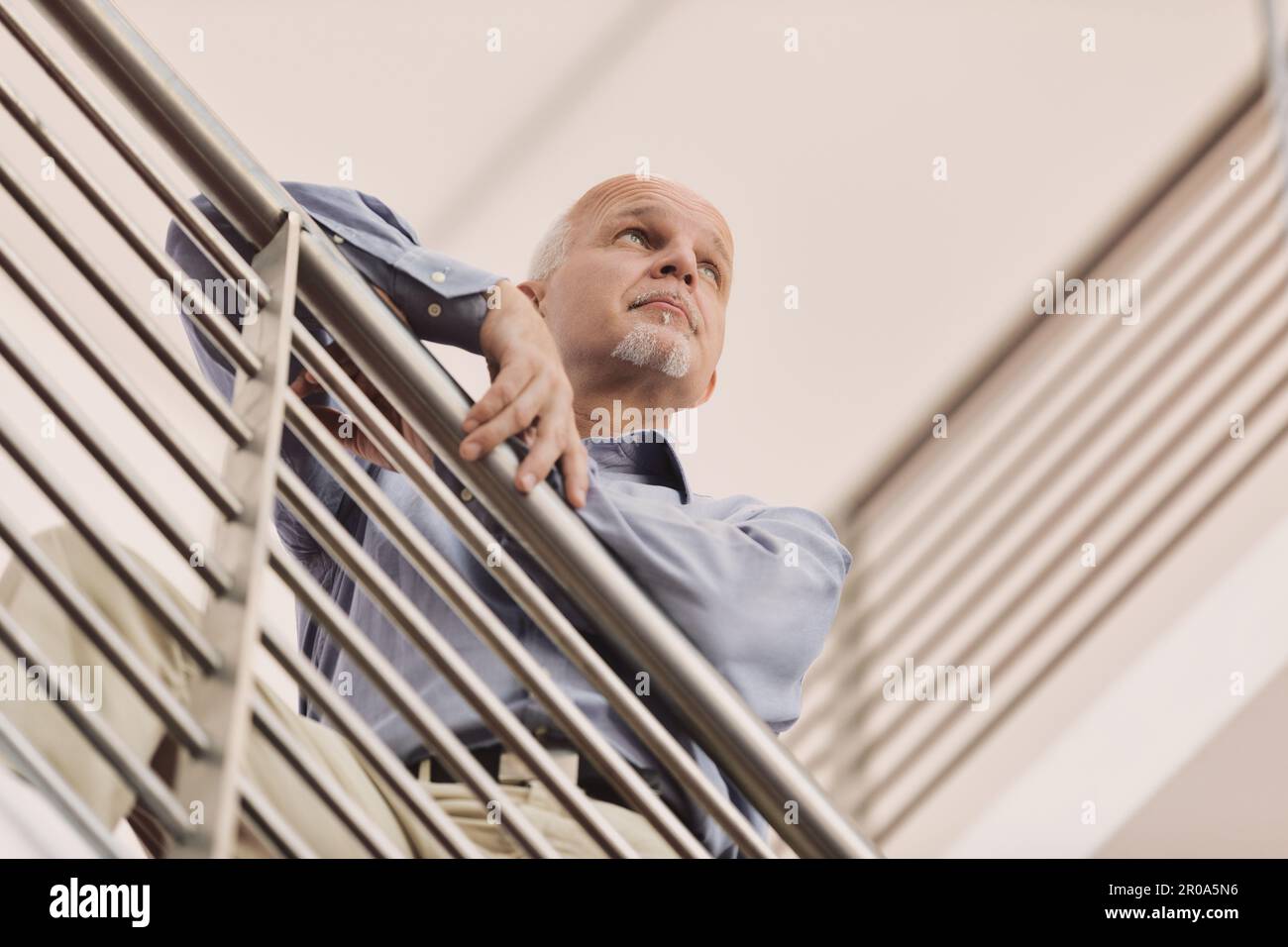 man leaning against modern railing seriously observes what is happening ...