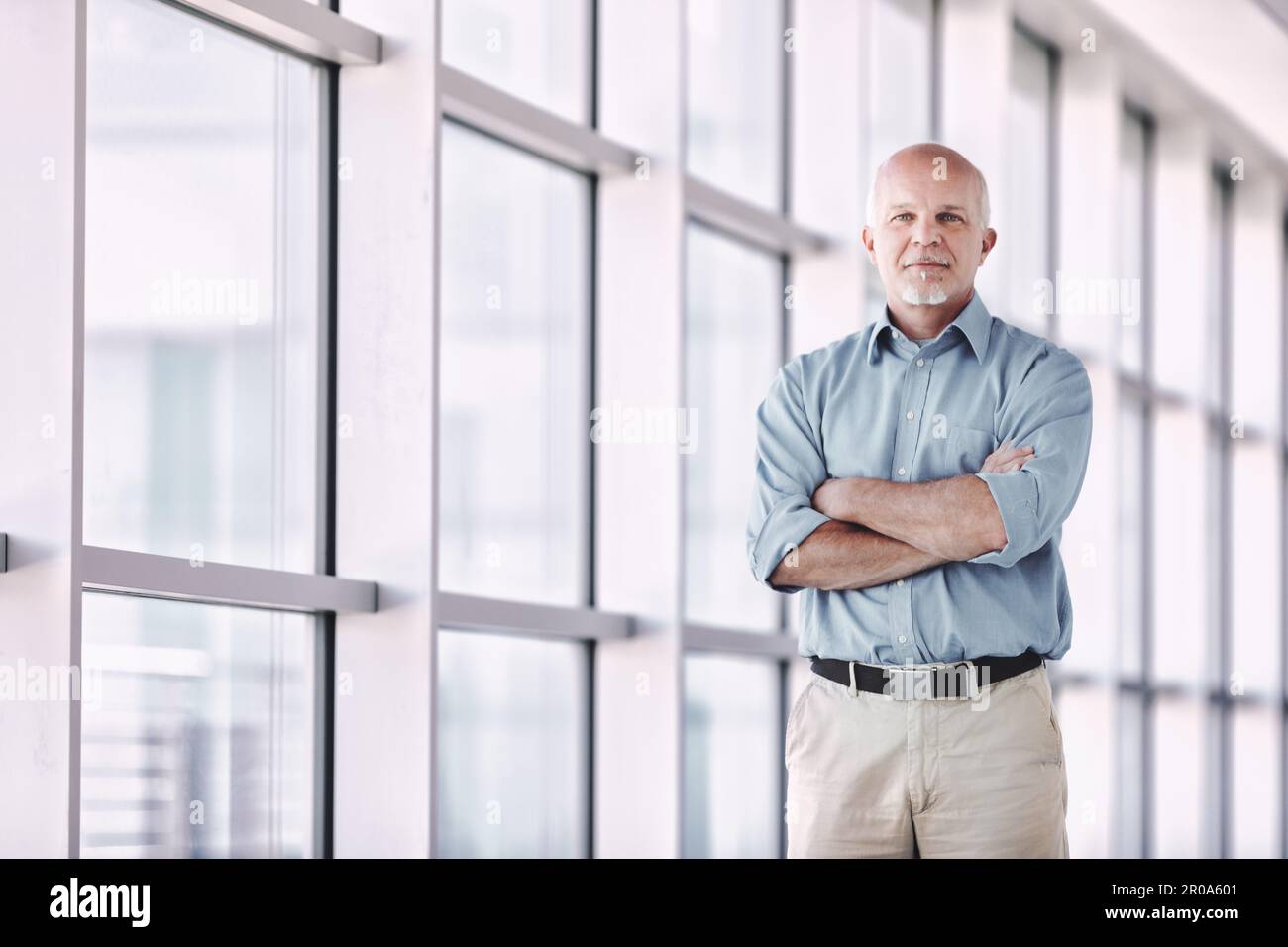 Smart man with his arms folded in modern bright corporate facilities ...