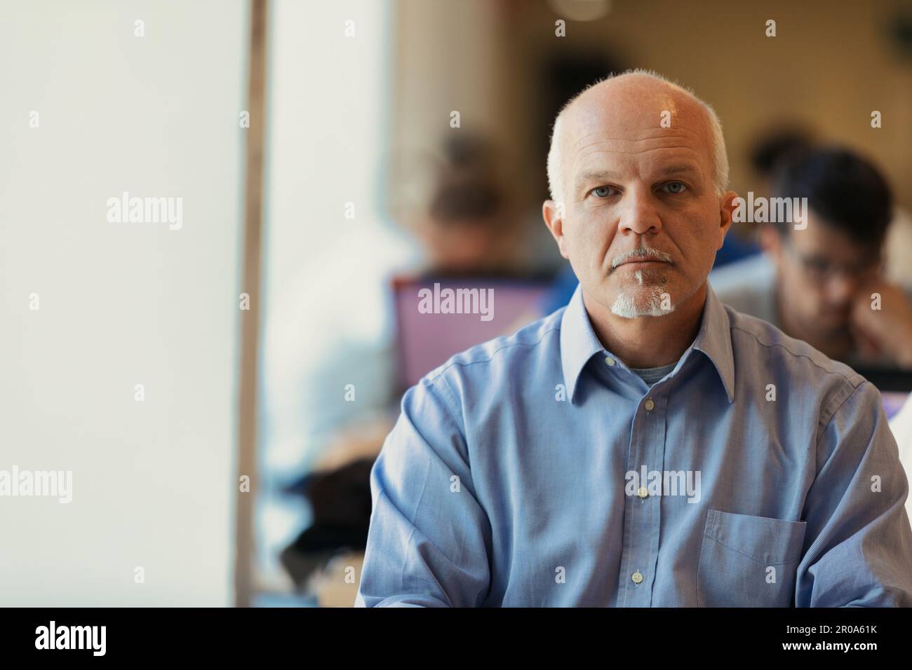 Middle-aged man sitting among other people out of focus and ...