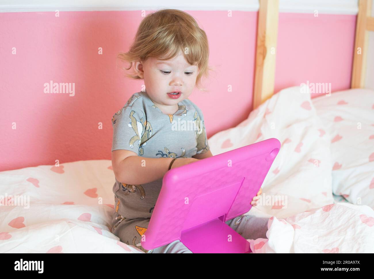 Cute Caucasian toddler girl watching tablet on the bed. Kids and ...