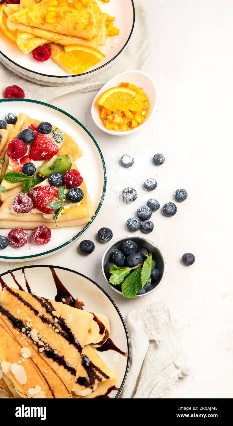 Variety of fresh crepes with chocolate, jam, fruits and berries on ...
