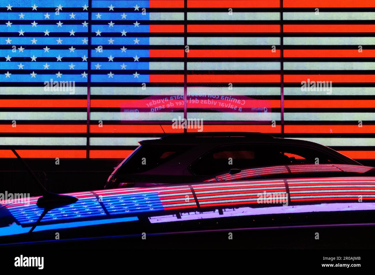 Cars pass in front of an illuminated flag in New York City’s Times ...