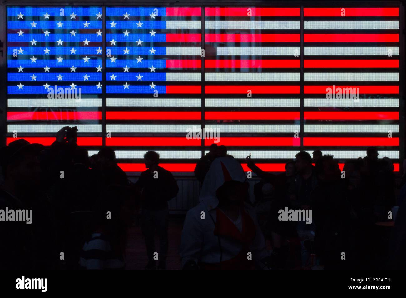 A crowd gathers in front of an illuminated flag in New York City’s ...